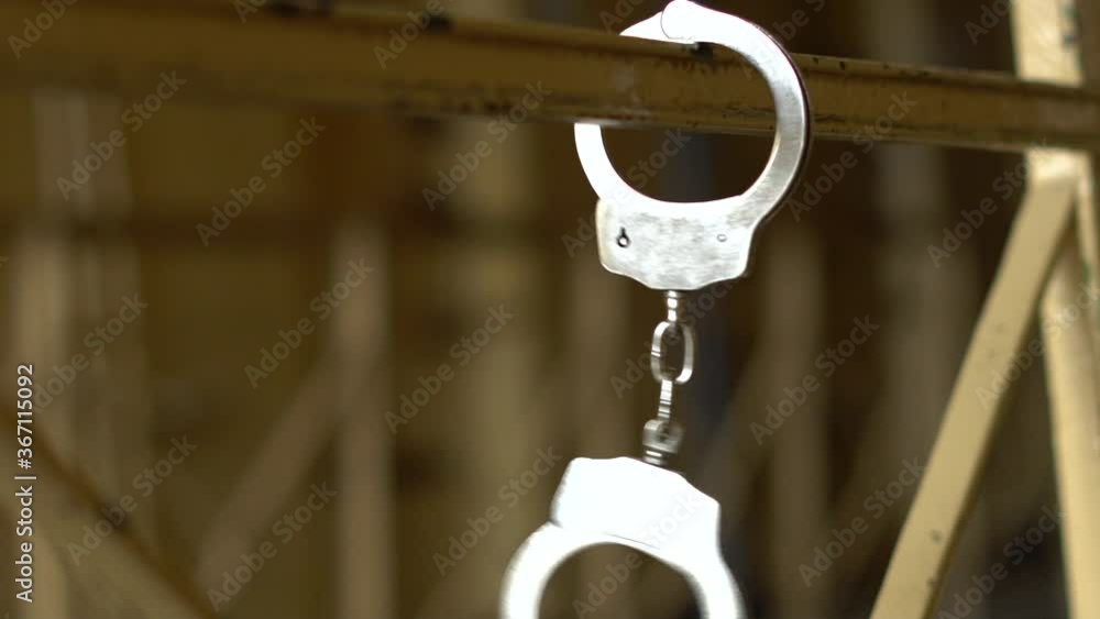 Handcuffs swinging on the handrail on a prison or arrest background ...