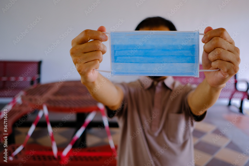 Man holding up surgical mask in neighbourhood. Now mandatory to wear ...