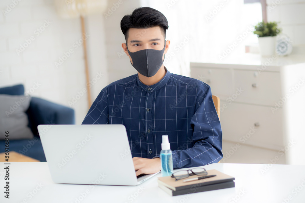 Young business man in face mask working from home with laptop computer ...