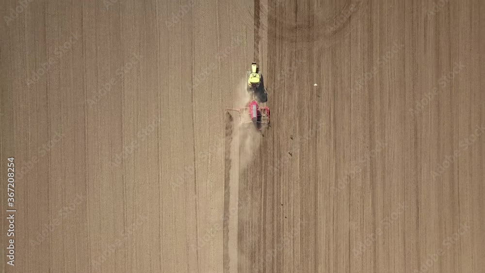 Top down aerial view of green tractor cultivating ground and seeding a ...