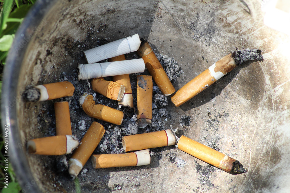 Old dirty cigarette butts in an iron bowl Stock Photo | Adobe Stock
