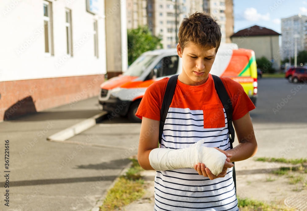 Teenage with broken hand in a cast in front of ambulance in the city ...