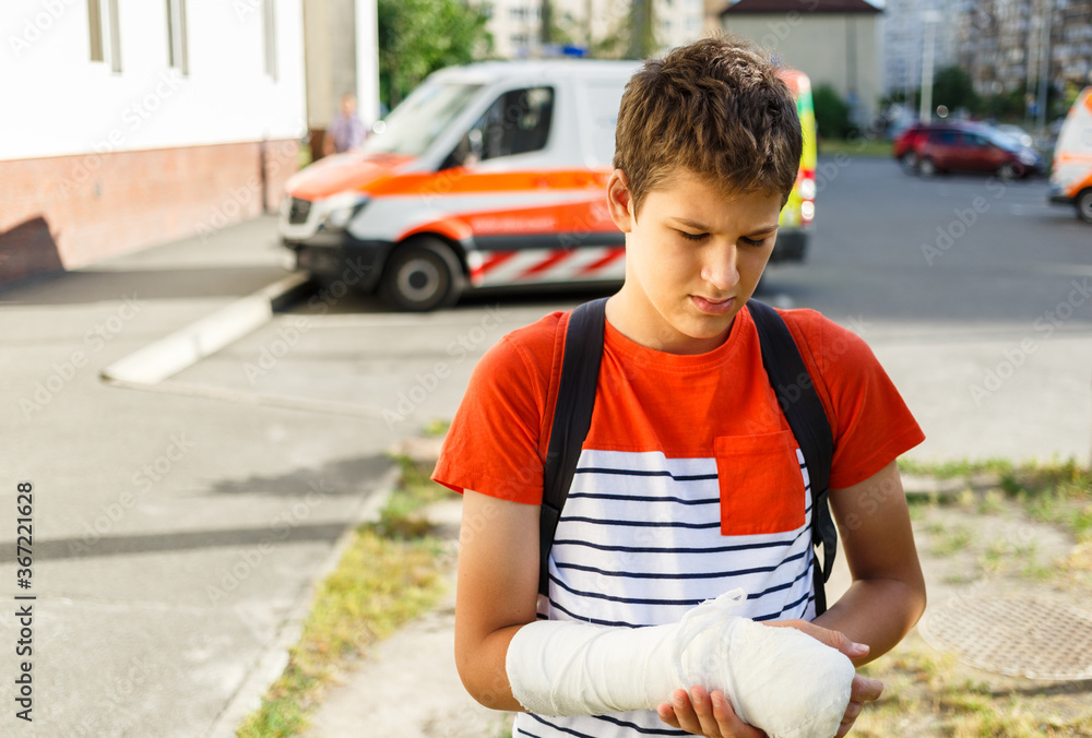 Teenage with broken hand in a cast in front of ambulance in the city ...