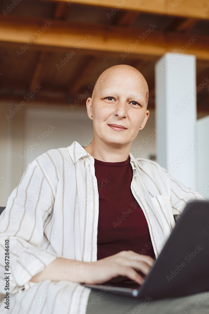 Vertical portrait of bald adult woman smiling at camera while holding ...