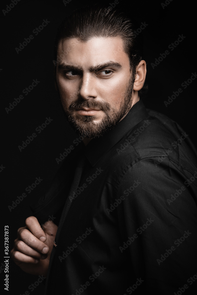 Strict male portrait. The guy in the classic black suit. Half face in ...