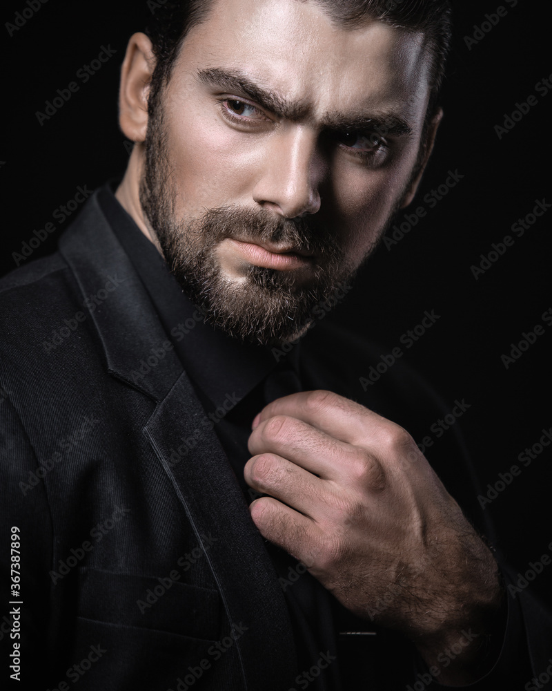 Strict male portrait. The guy in the classic black suit. Half face in ...