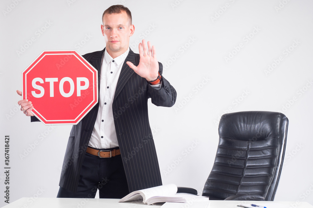 The man makes a warning gesture with his hand and holds a Stop sign. A ...