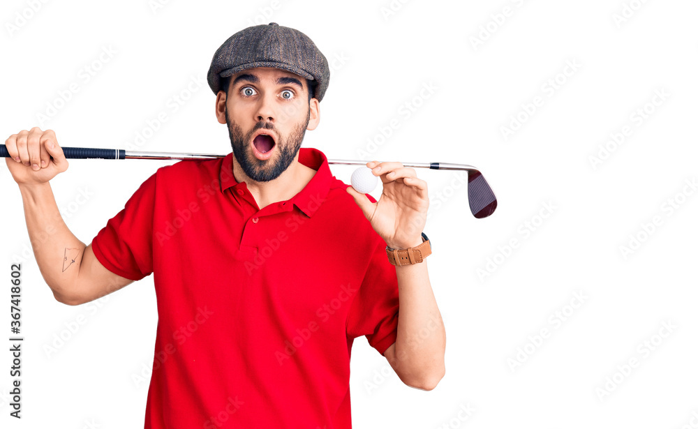 Young handsome man with beard playing golf holding club and ball scared ...