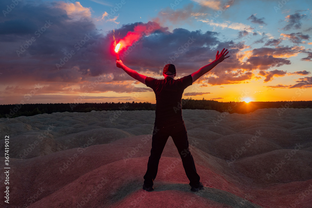 Man greets the sun. A man with a smoke torch stands facing the rising ...