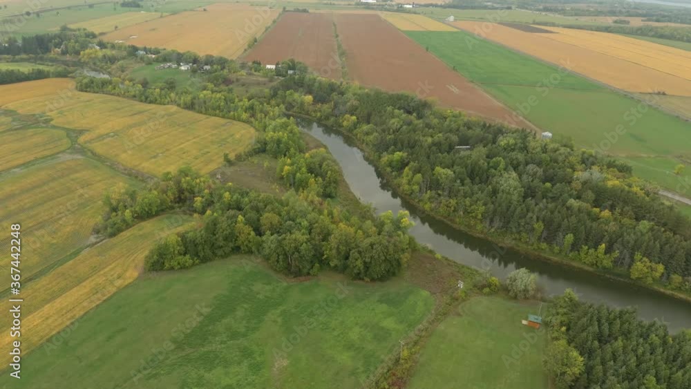 Rural farmlands with river running through and trees growing on each ...