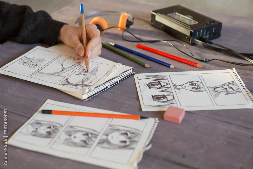 Artist drawing an anime comic book in a studio. Wooden desk, natural ...