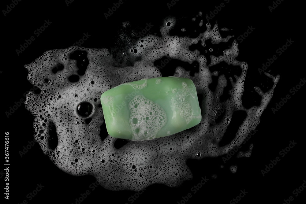 Green soap bar with foam, lather bubbles isolated on black background ...