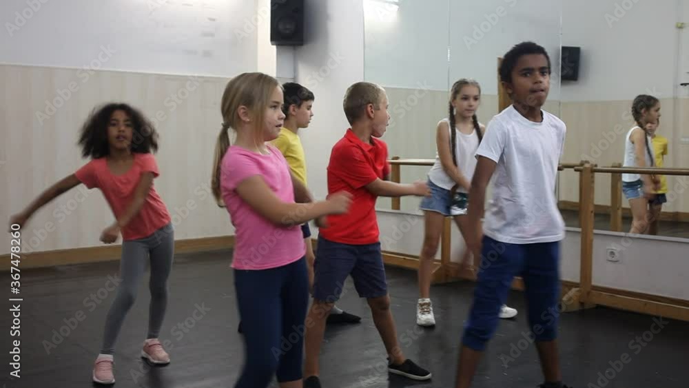 Preteen boys and girls with female trainer practicing floss dance ...