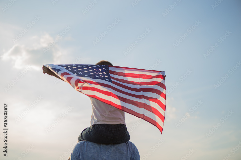 Little boy lets the american flag fly in his hands on the wind at the ...