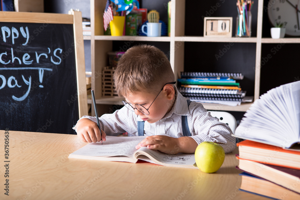 Cute Kid is learning in class on background of blackboard. Teachers day ...