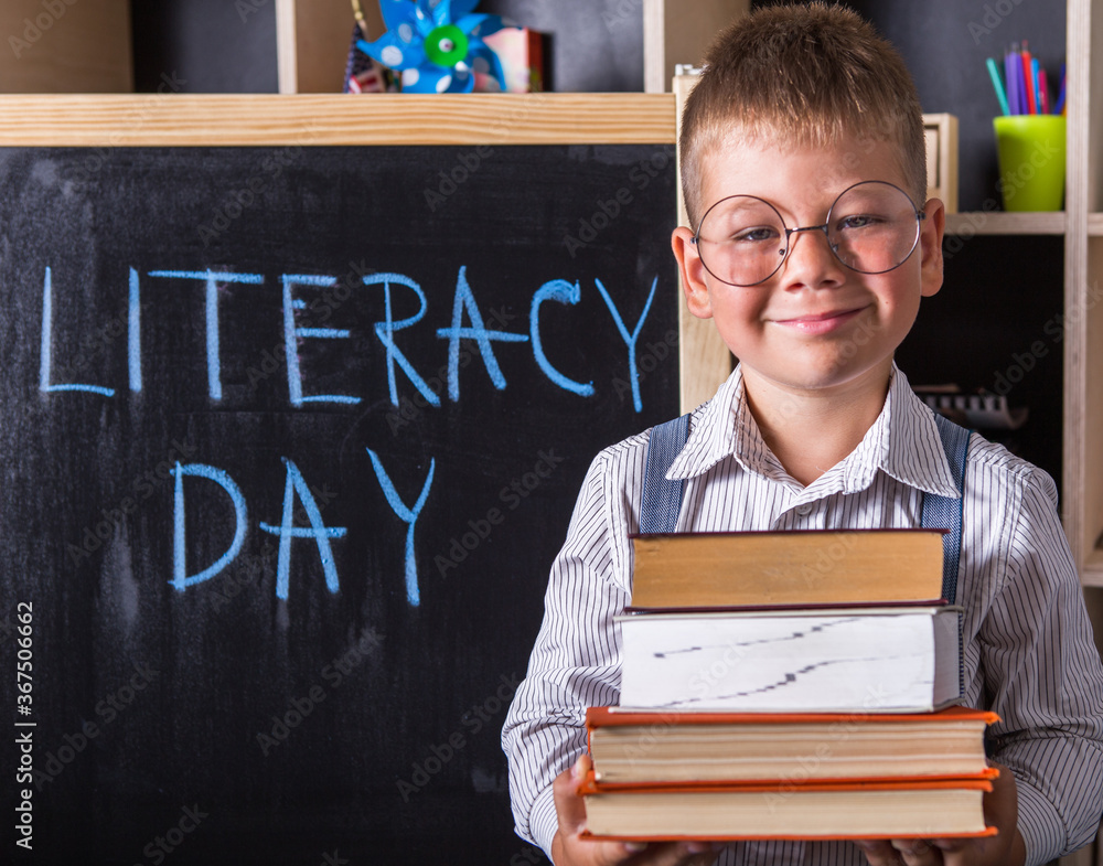 Portrait of cute little boy holding book in classroom. Happy ...
