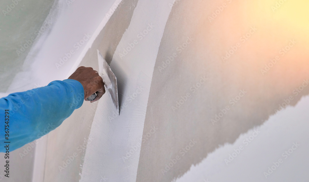Builder using plastering tool for finishing wall in the construction ...