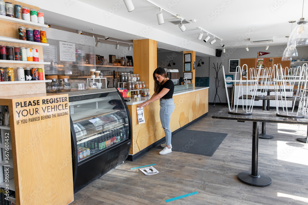 Young woman putting safety distance poster on cafe counter Stock Photo ...