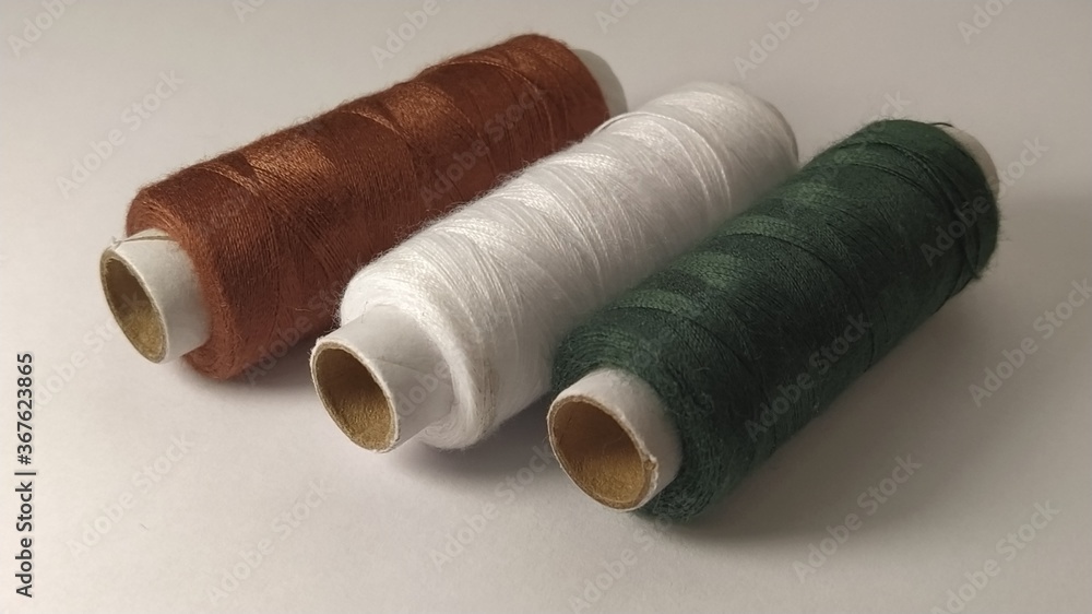 Bobbins and spools of thread of different colors - brown, white and ...