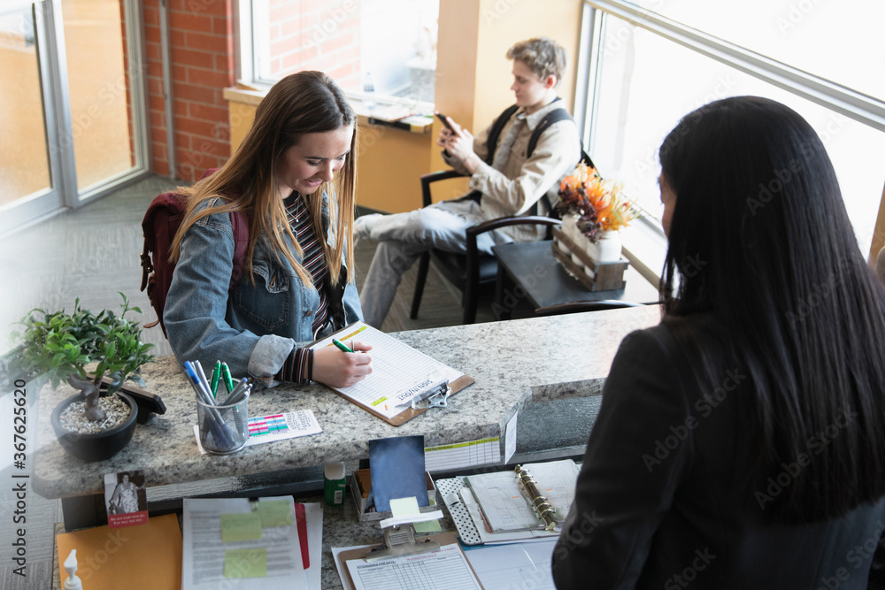 High school girl student filling out paperwork in school office Stock ...