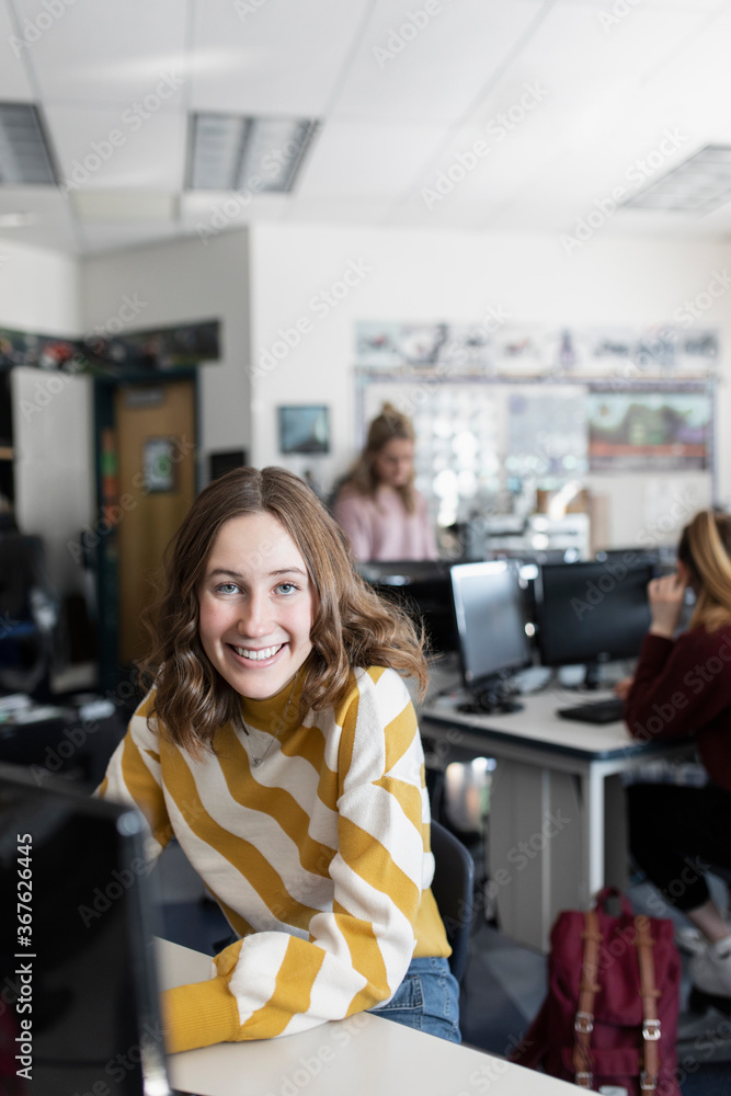Portrait happy high school girl student using computer in classroom ...
