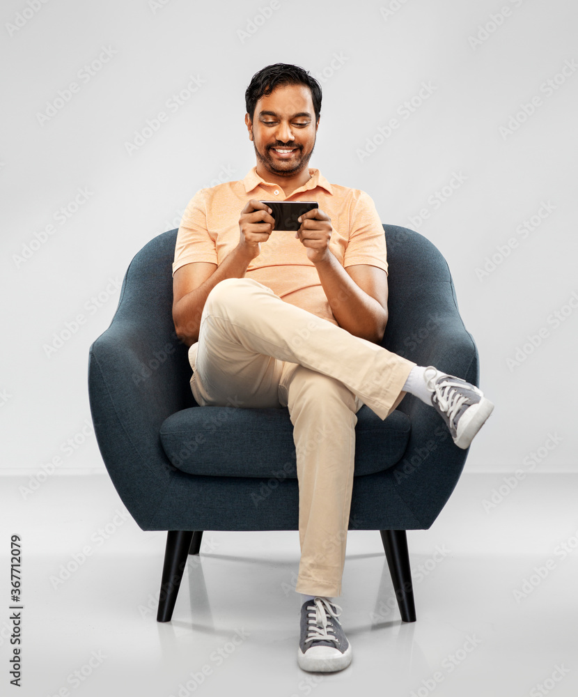 people, technology and furniture concept - happy smiling young indian ...