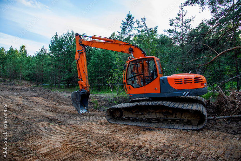 Excavator clearing forest for new development. Orange Backhoe modified ...