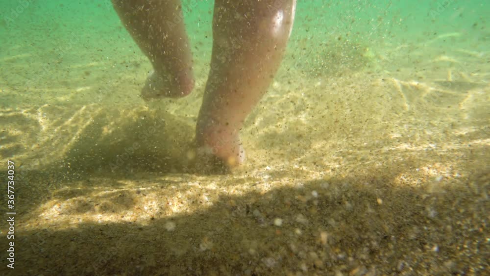 Little infant baby child legs and toes touch sand on sea beach. Happy ...