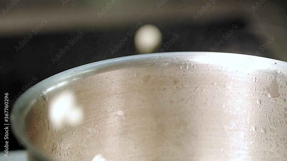 Yellow popcorn seeds exploding and flying up from a hot metal frying ...