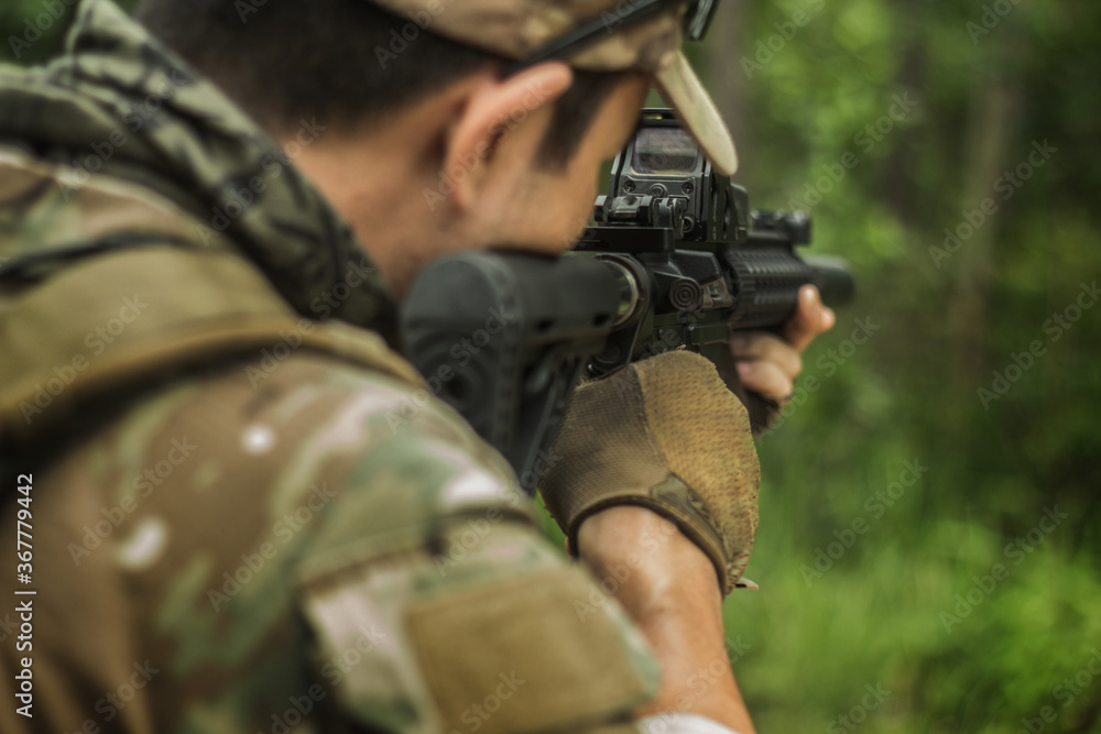 Military shooter with his precising assault rifle aiming and shooting ...