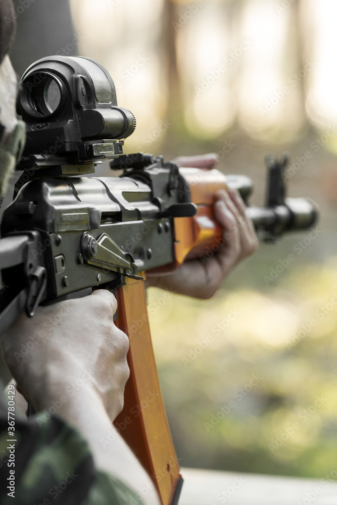Military shooter with his precising assault rifle aiming and shooting ...