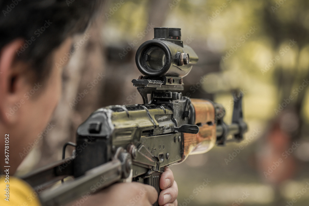 Military shooter with his precising assault rifle aiming and shooting ...