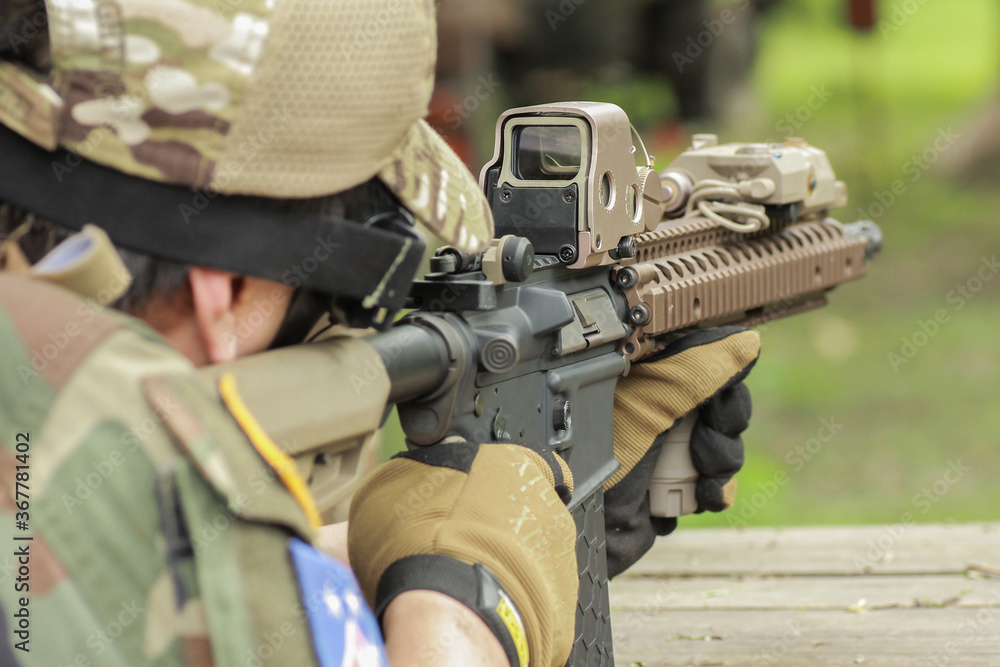 Military shooter with his precising assault rifle aiming and shooting ...