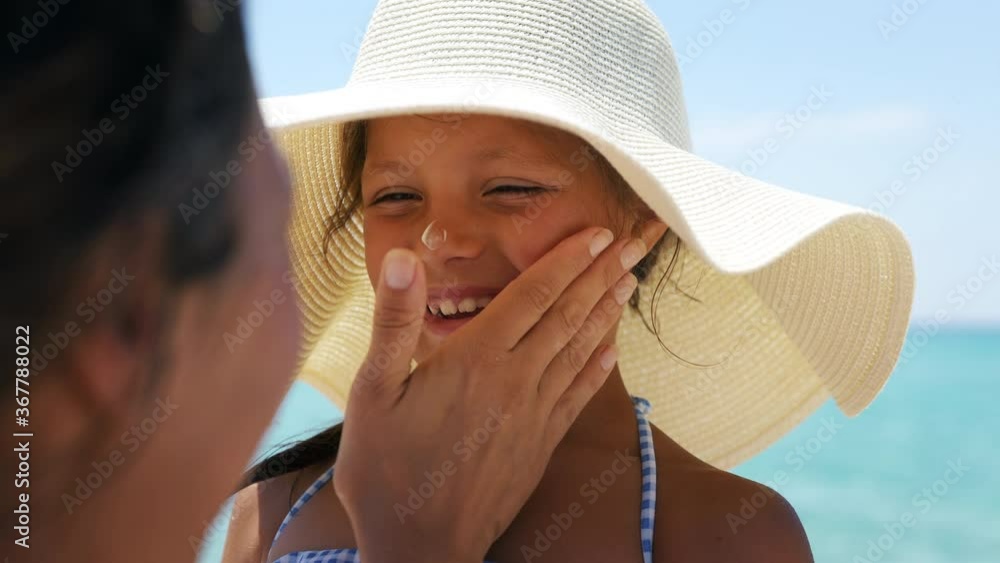 Close up of young mother is applying protective sunscreen or sunblock ...