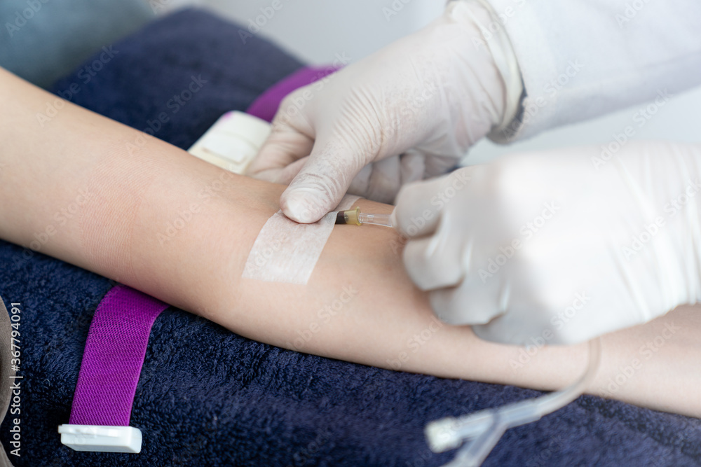 Doctor hand put intravenous(IV) injection on patient arm for drip ...