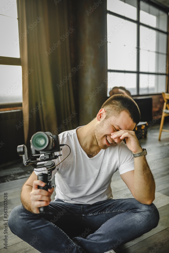 Handsome young cameraman in white T-shirt jeans and sneakers smiling ...
