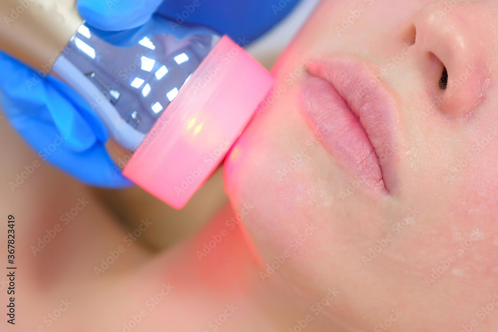 Portrait of woman on apparatus phonophoresis face procedure with ...
