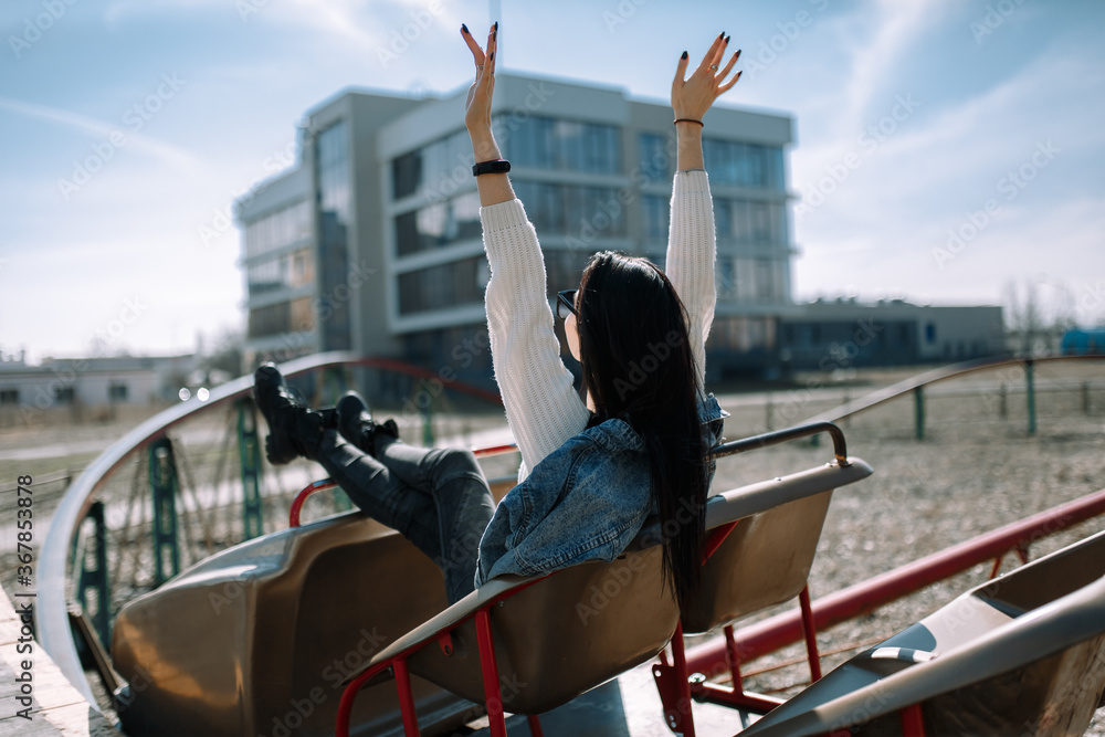 Fun roller coaster. Woman in a park with carousels under the bright sun ...
