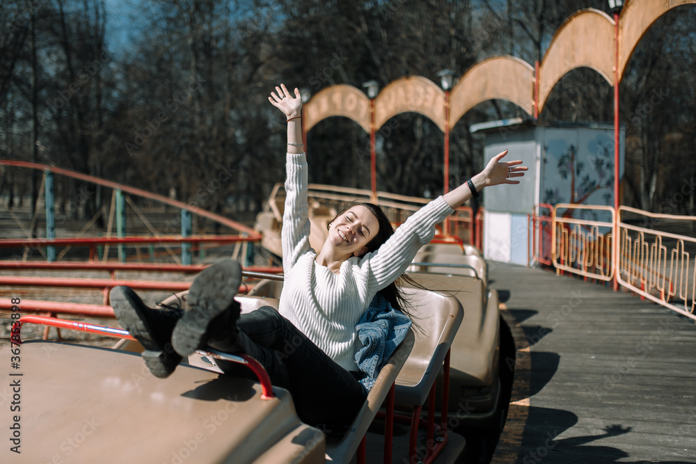 Fun roller coaster. Woman in a park with carousels under the bright sun ...
