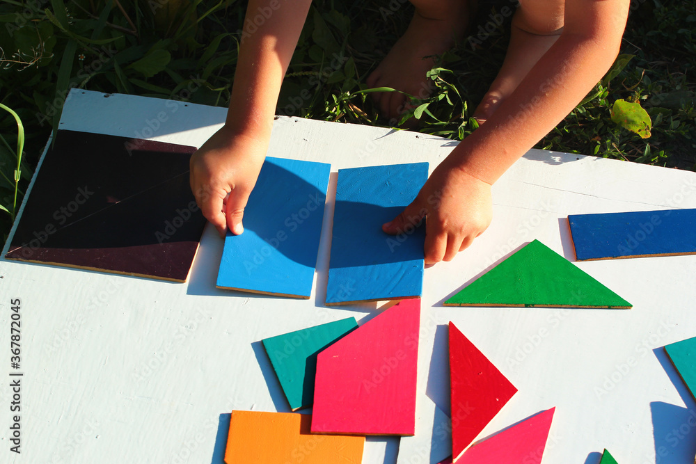 Little boy tries to solve the puzzle, moving different geometric shapes ...
