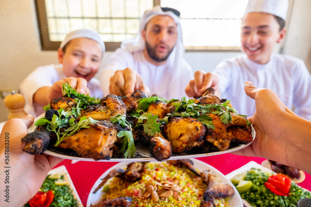 Arabic muslim family being picking chicken from plate being served for ...