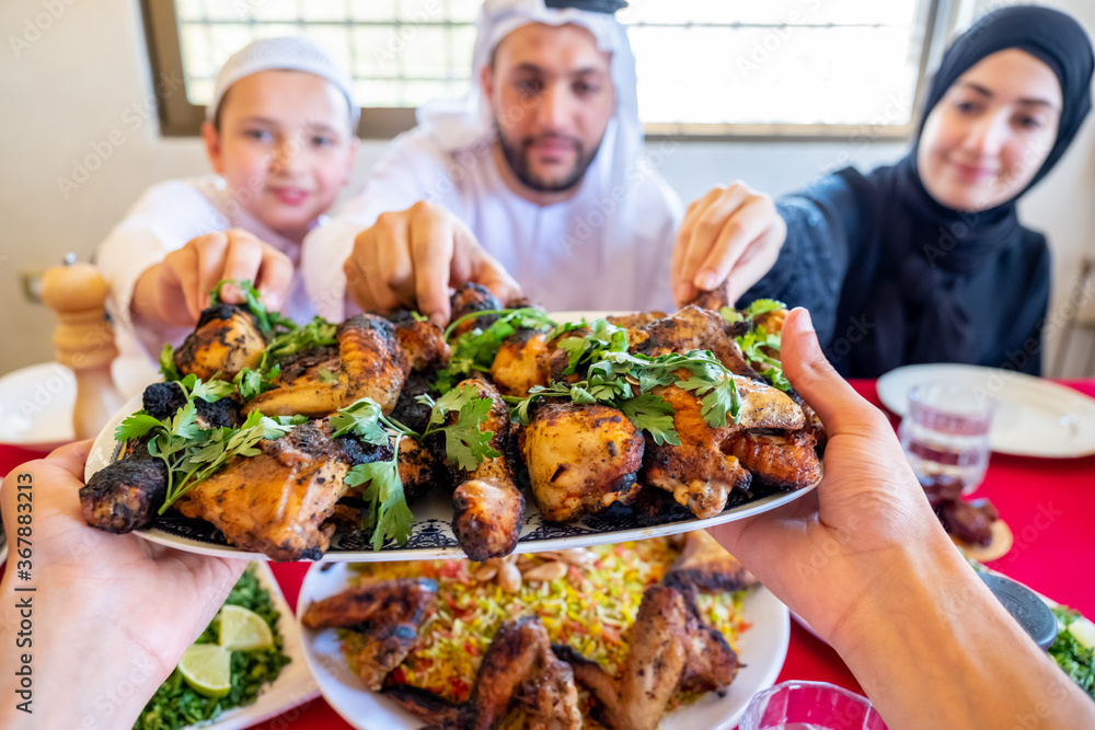 Arabic muslim family being picking chicken from plate being served for ...