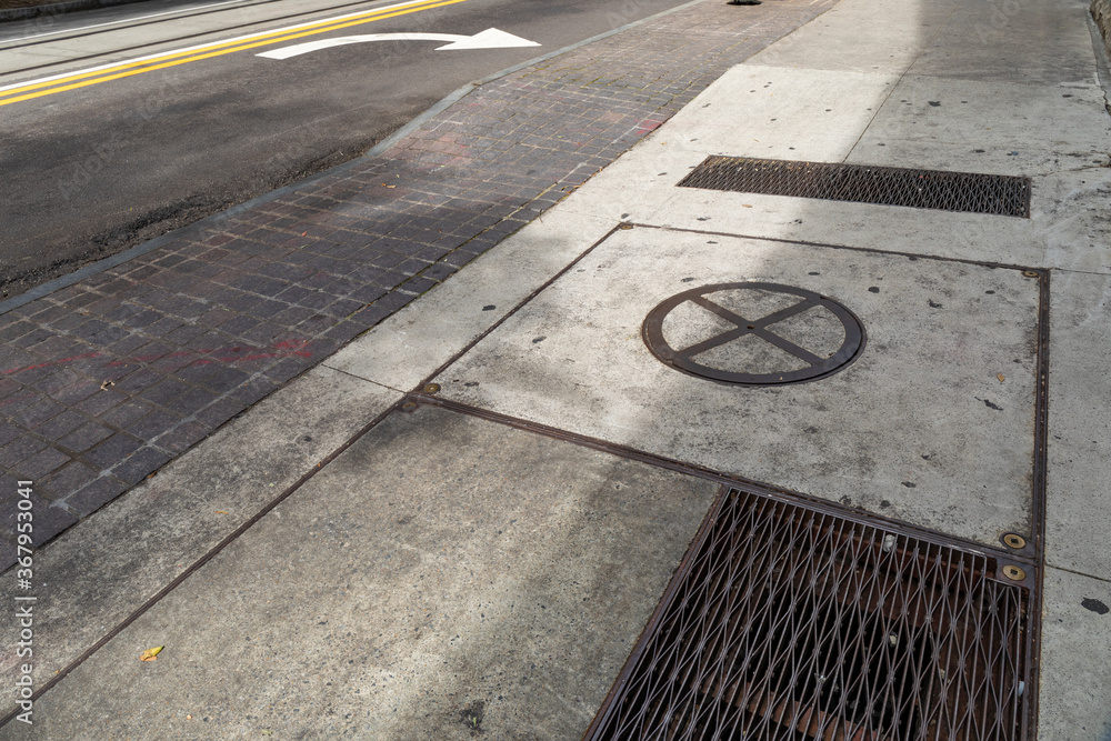 Dirty concrete and brick sidewalk alongside a street, turn lane arrow ...