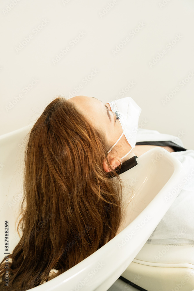 Young girl with long brown hair washing her head at the hairdresser's ...