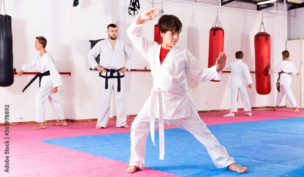 Preteen diligent glad cheerful boy practicing karate movements with ...