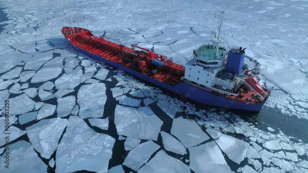 Aerial above epic huge steel icebreaker breaks ice by bow of ship and ...