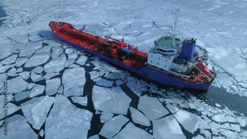Aerial above epic huge steel icebreaker breaks ice by bow of ship and ...