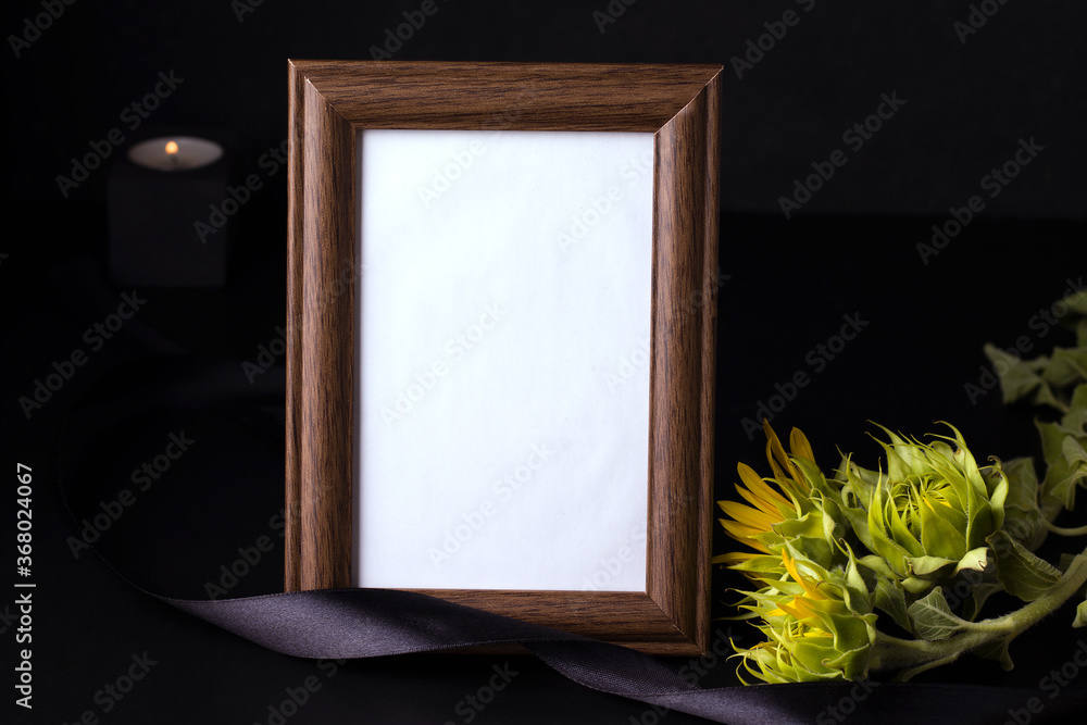 Obituary concept. Wooden photo frame empty next to flowers on black ...