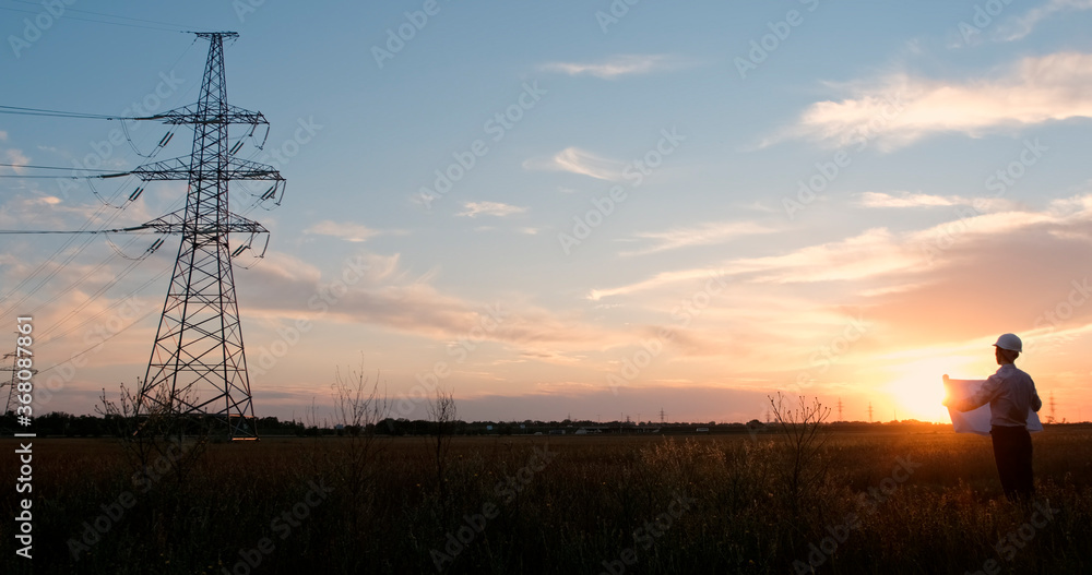An engineer with a poster stands in the middle of a field and looks ...