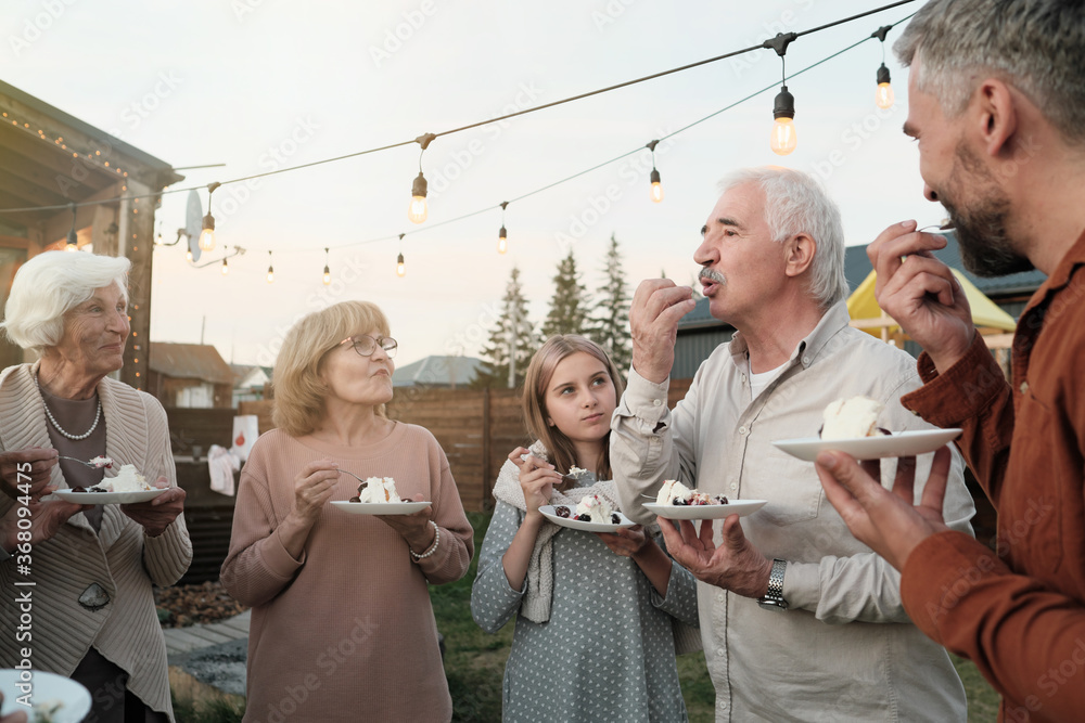 Big family standing in the circle and eating cake together during party ...